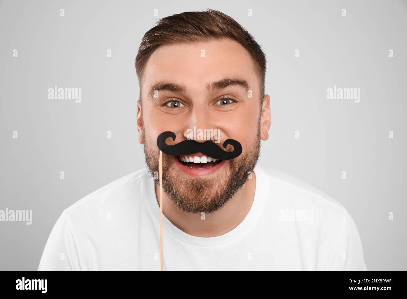 Funny man with fake mustache on light grey background Stock Photo - Alamy