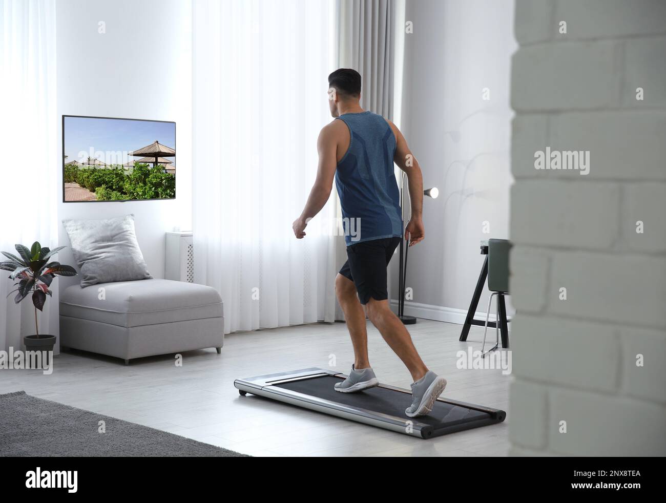 Sporty man training on walking treadmill and watching TV at home Stock ...
