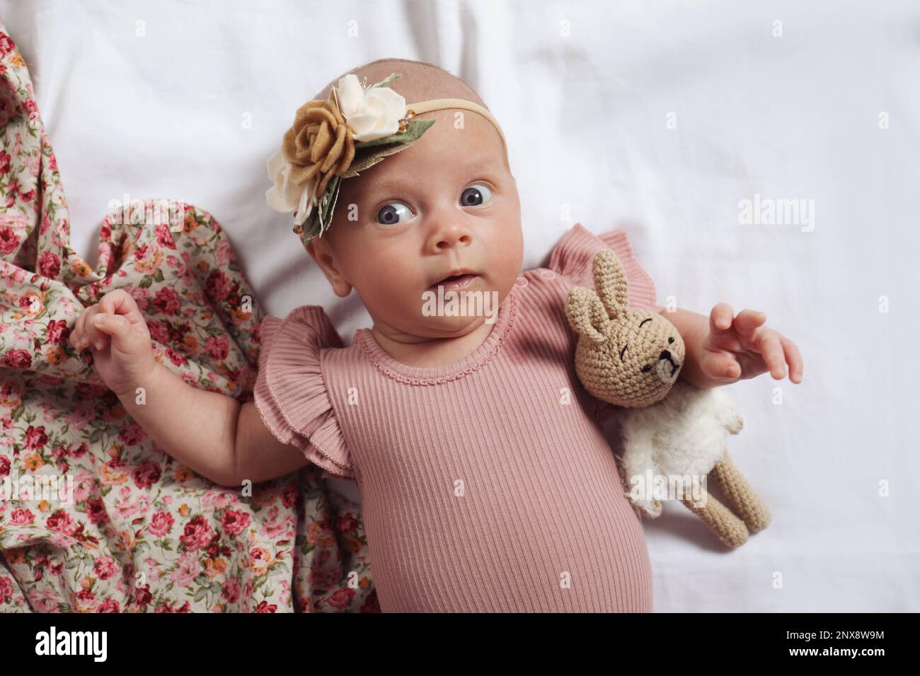 Cute newborn baby girl with floral headband on bed, top view Stock Photo - Alamy