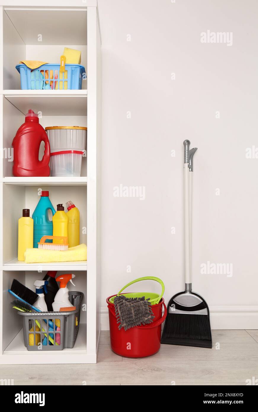 Shelving unit with detergents and cleaning tools near white wall ...