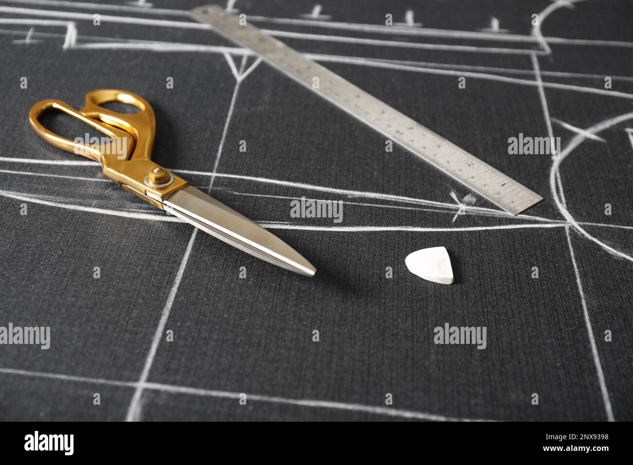 Scissors, tailor's chalk and ruler on grey fabric with sewing patterns ...
