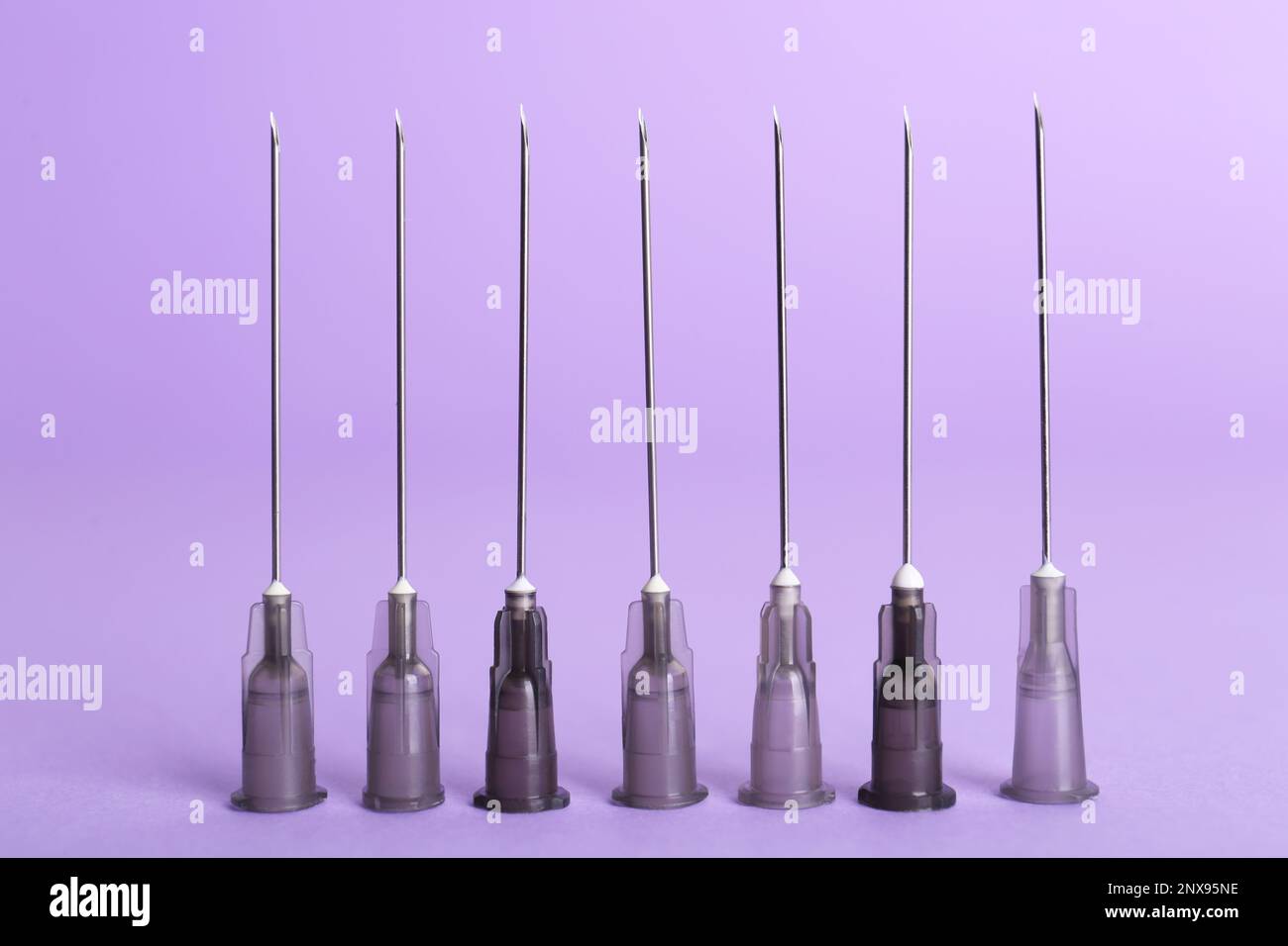 Many disposable syringe needles on violet background Stock Photo - Alamy