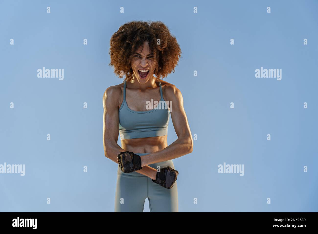 Sporty woman flexing muscles with energy to show off her biceps and ...