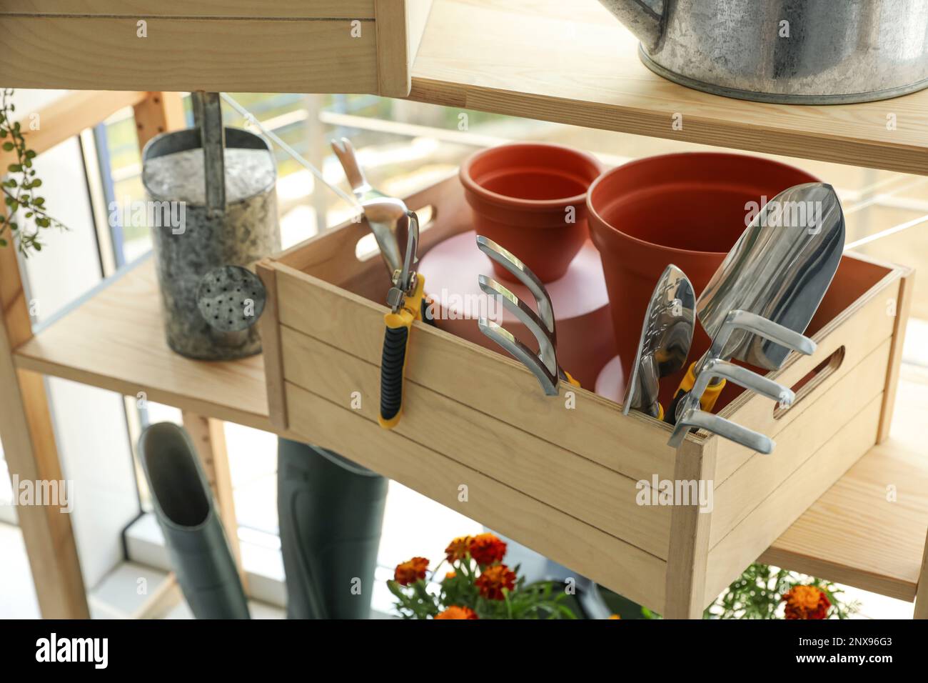 Wooden crate with gardening tools on rack indoors Stock Photo - Alamy