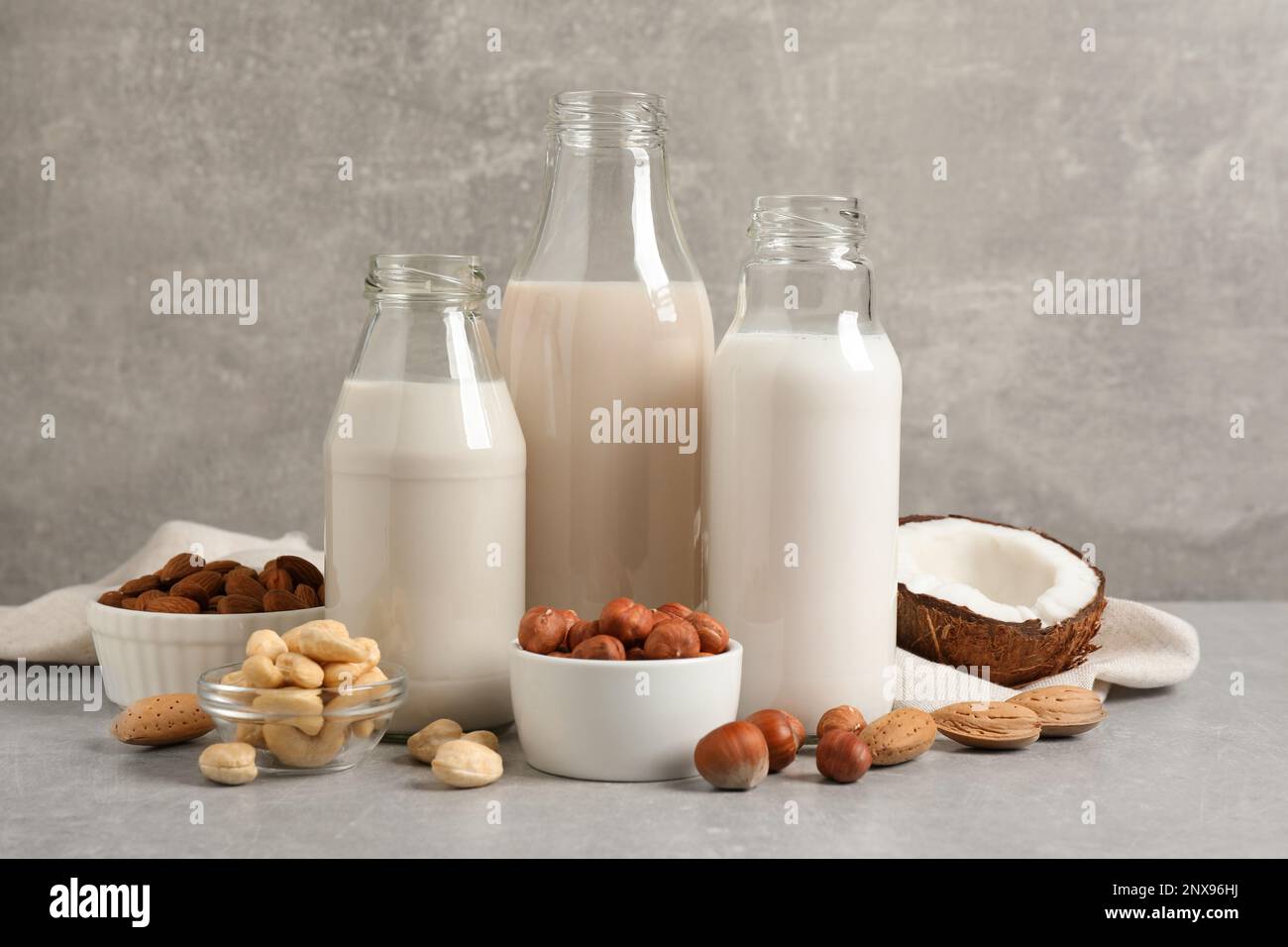 Different nut milks on light grey table Stock Photo - Alamy