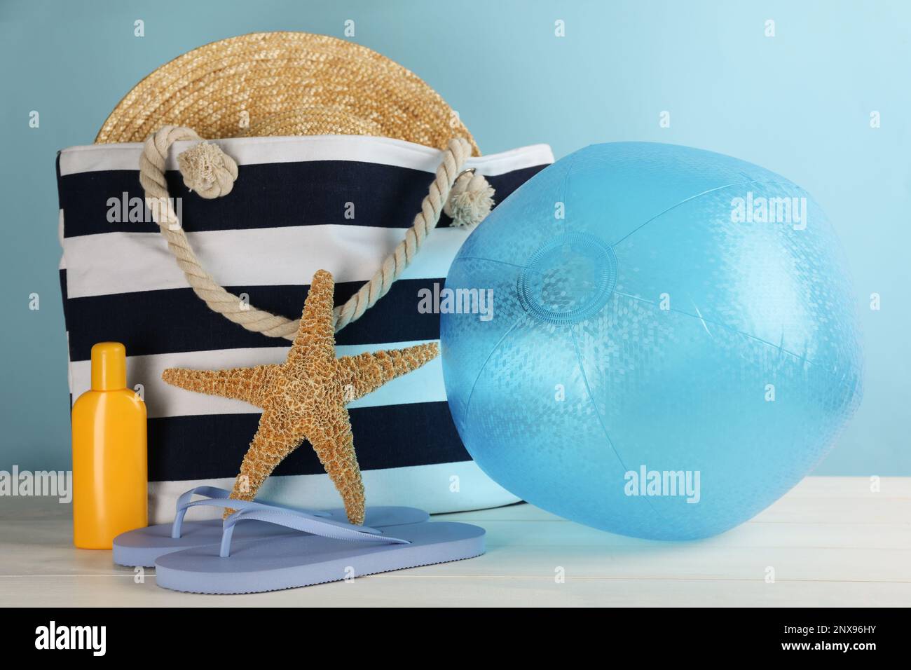 Light blue inflatable ball and different beach accessories on white ...