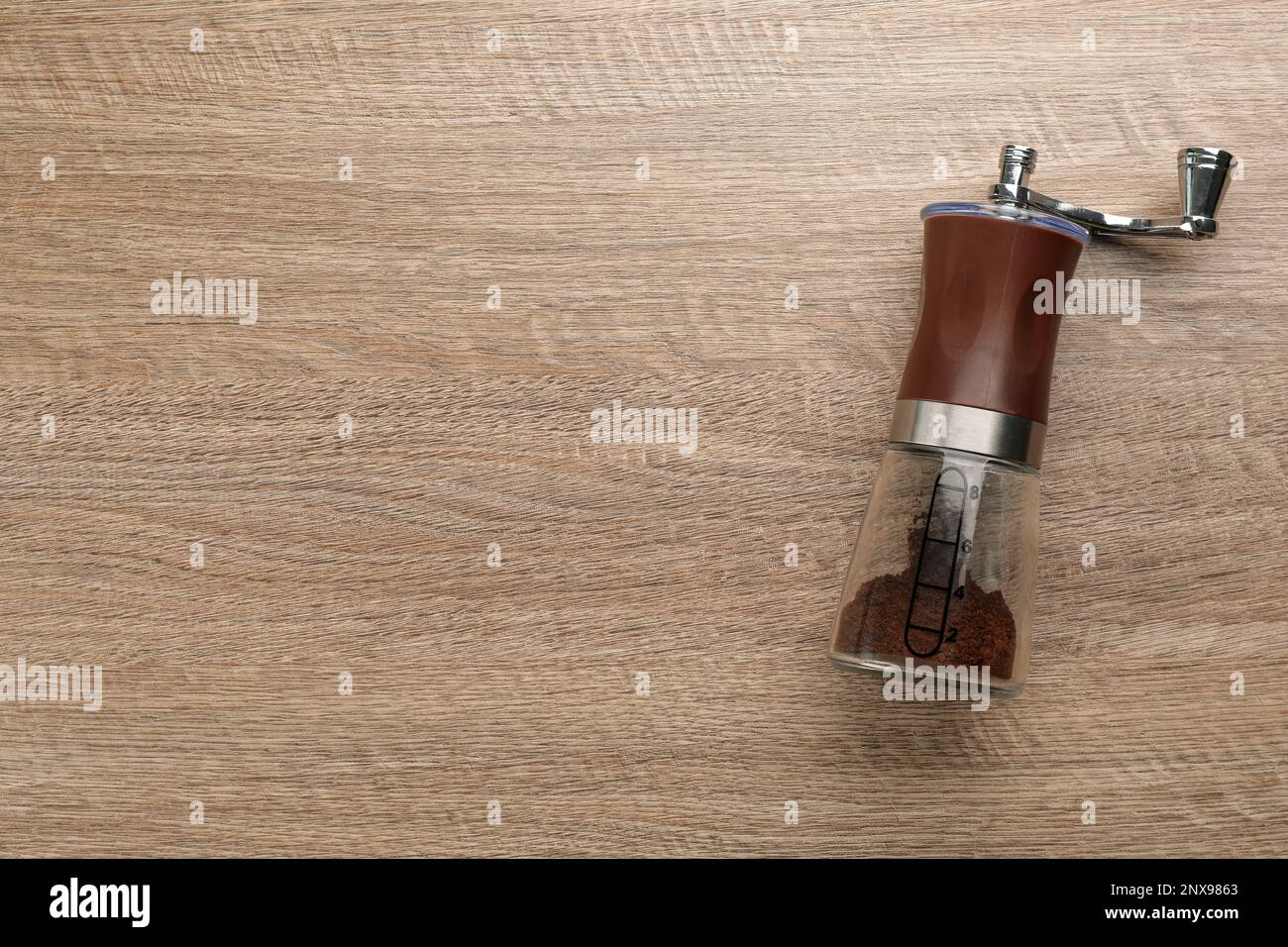 Modern manual coffee grinder on wooden table, top view. Space for text ...