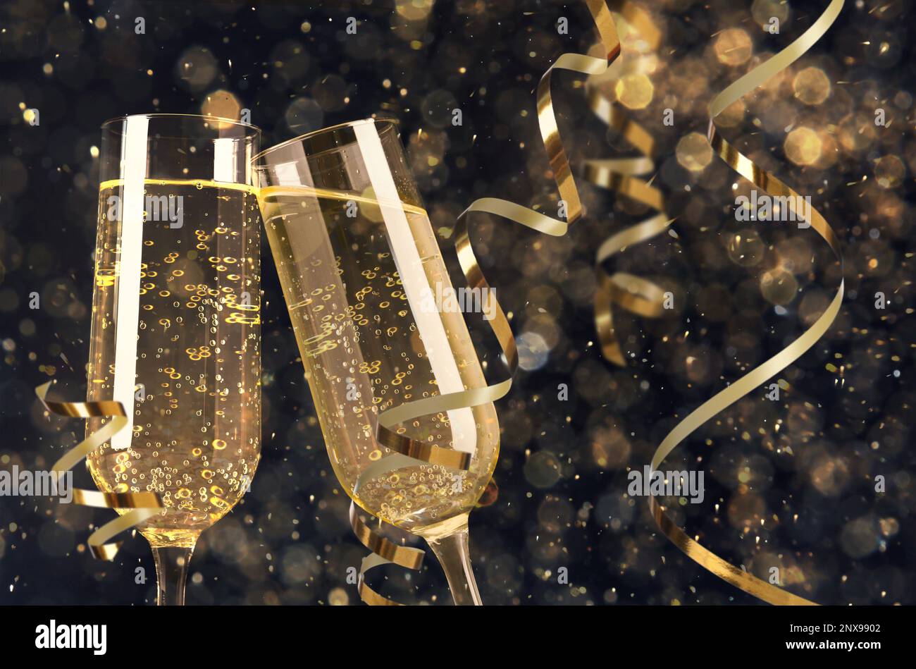 Glasses with sparkling wine and shiny serpentine streamers against ...
