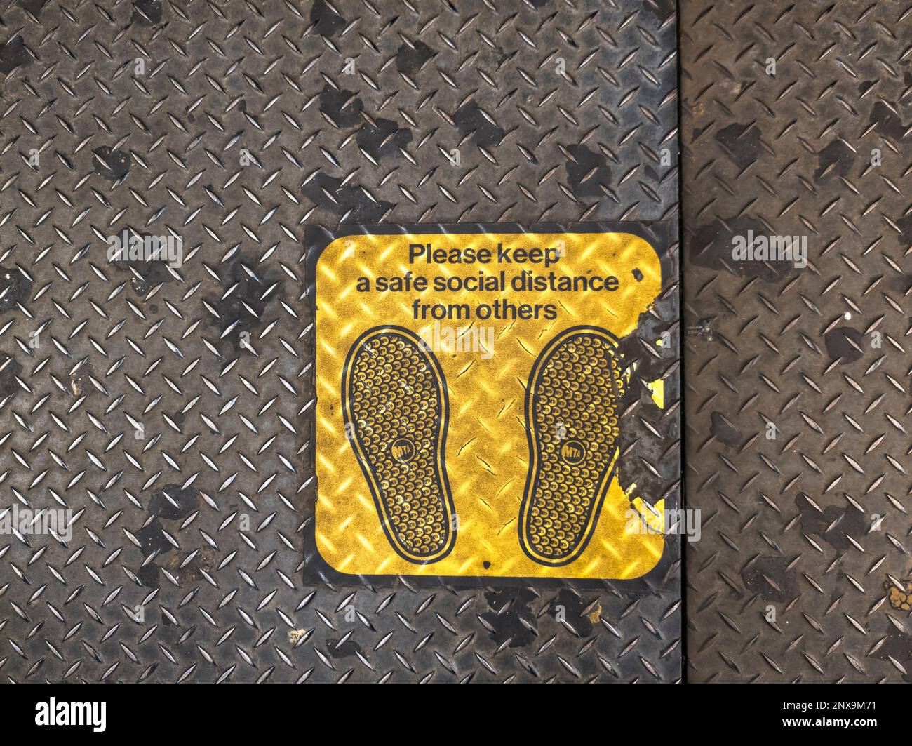 A worn social distancing sticker on the floor of a platform in the ...