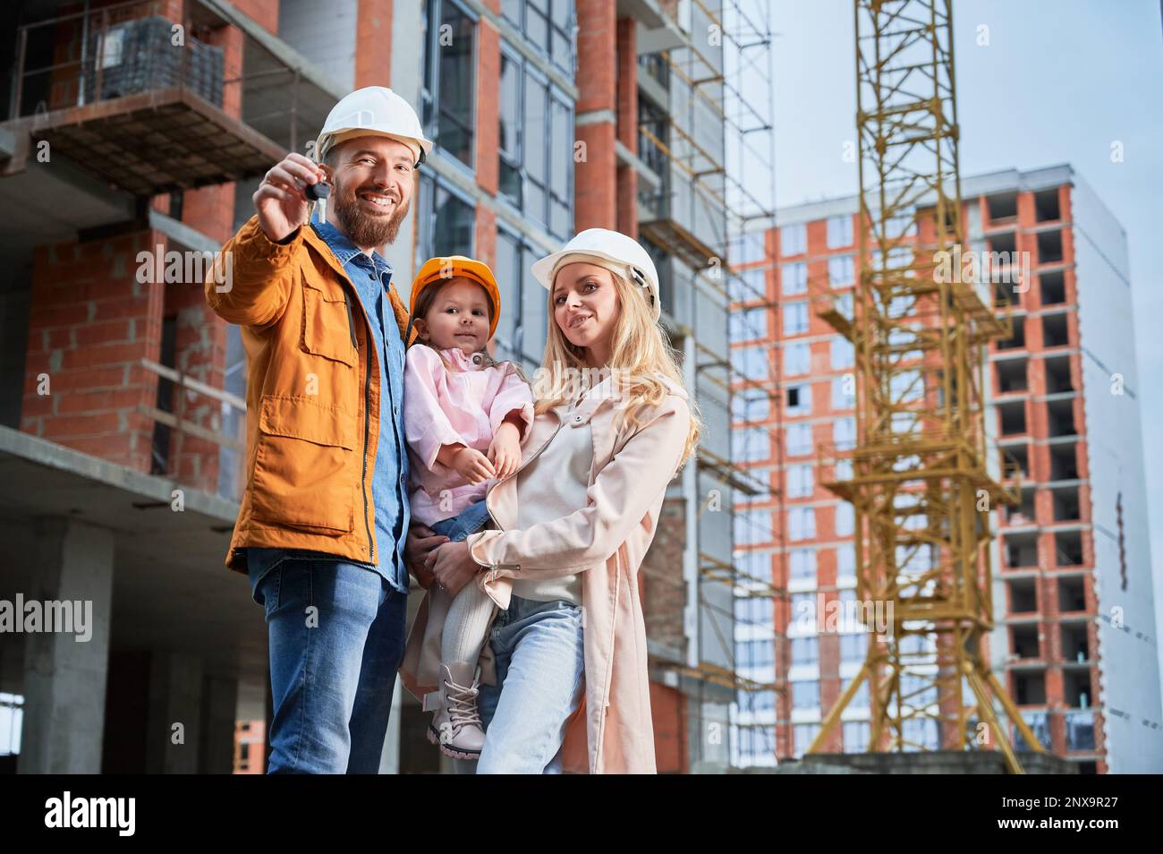 Man holding apartment keys and smiling while standing next to wife and ...