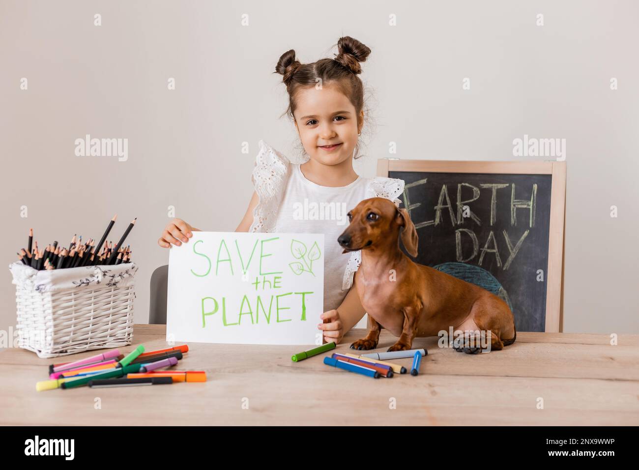 a cute little girl drew a sign save the planet with her pet dog ...