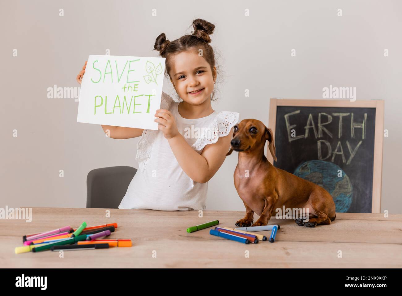 a cute little girl drew a sign save the planet with her pet dog ...