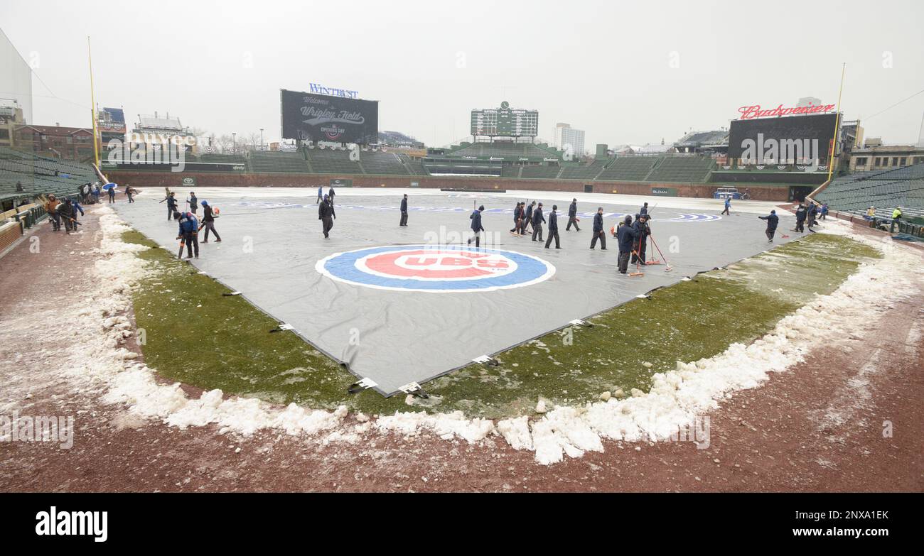 Workers clear snow as the baseball game between the Chicago Cubs and ...