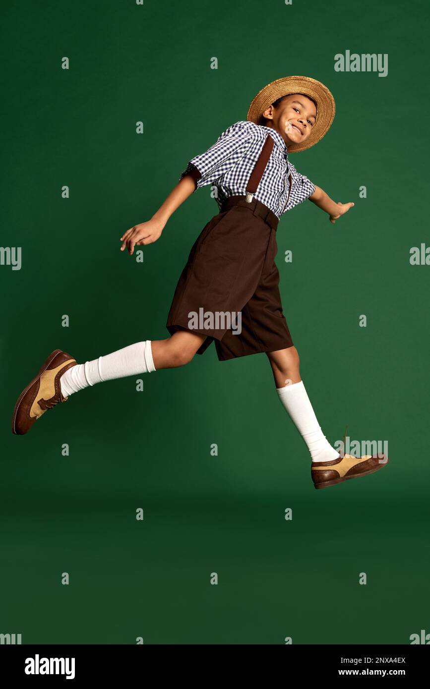 Happy little boy, child in checkered shirt and suspender shorts jumping ...