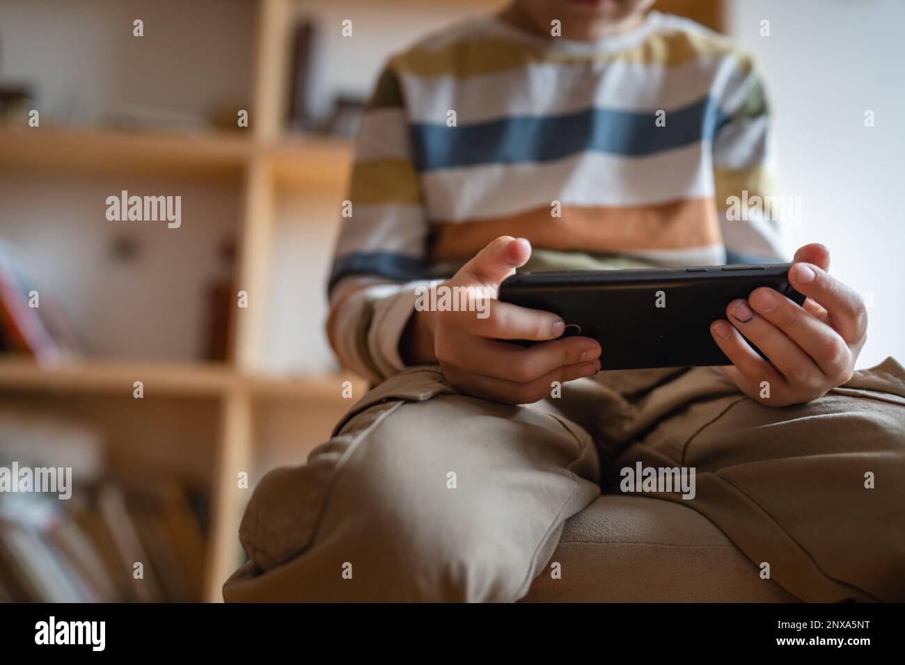 hand of boy caucasian child hold smartphone mobile phone at home play ...