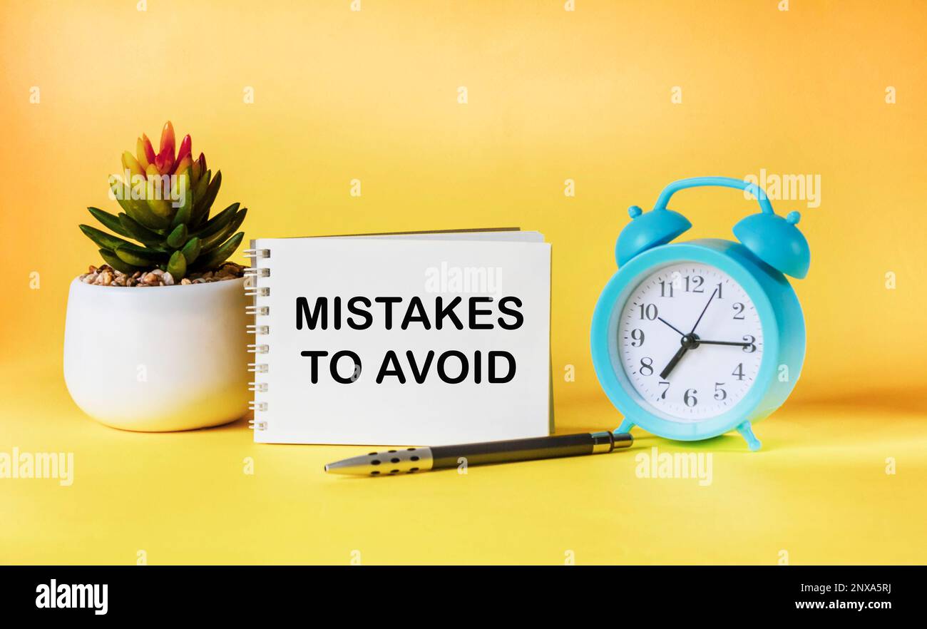 Notepad with text errors to avoid, clock and cactus on yellow ...