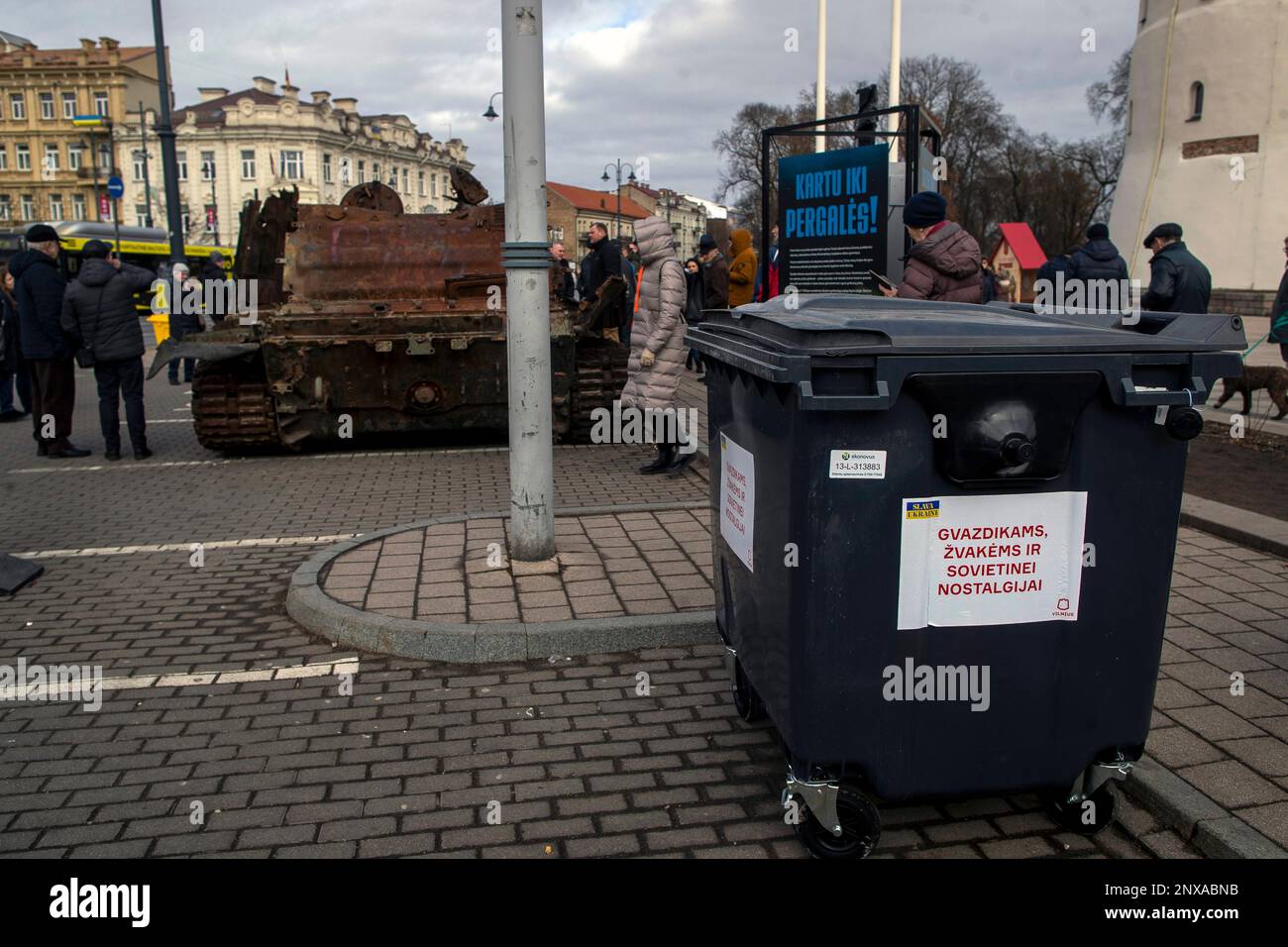 A garbage container displays a sign with writing reading "For ...