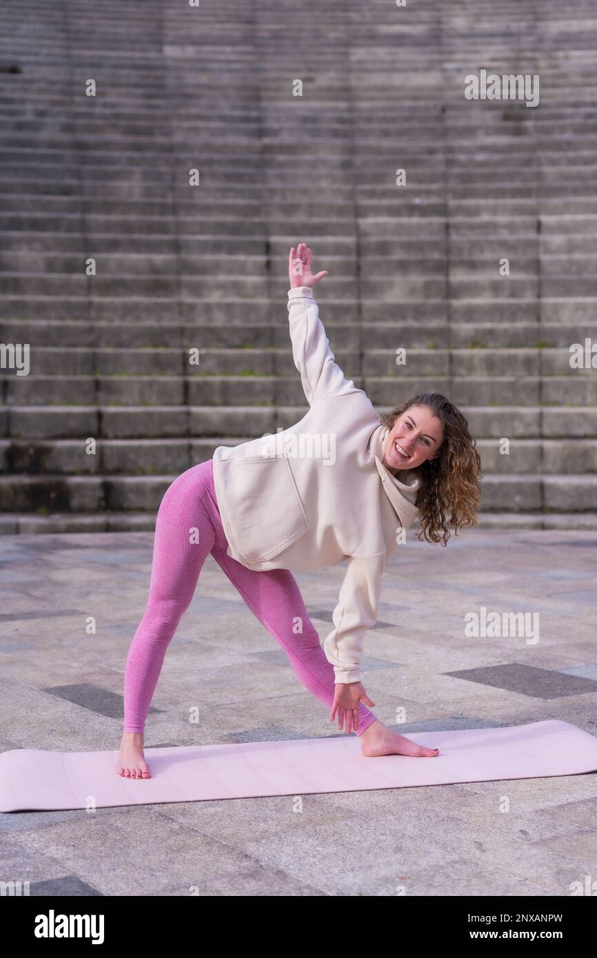 A vertical shot of a young caucasian woman doing the revolved triangle ...