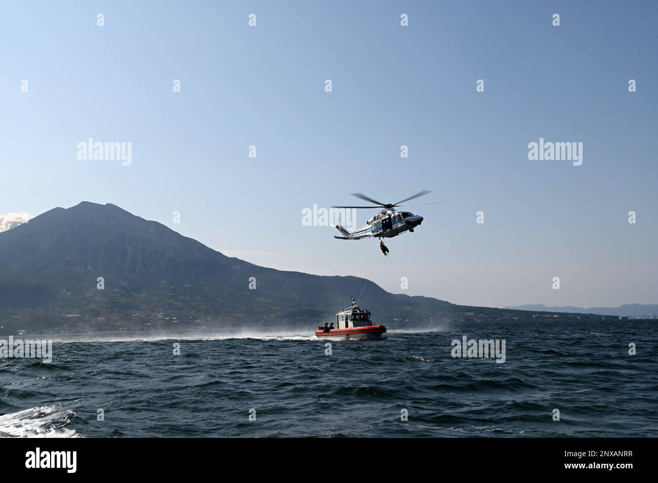 A Japan Coast Guard Mobile Rescue Technician hoists a simulated swimmer ...