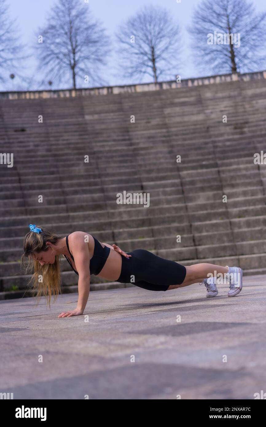 A vertical shot of a young caucasian woman doing the push-up exercise ...