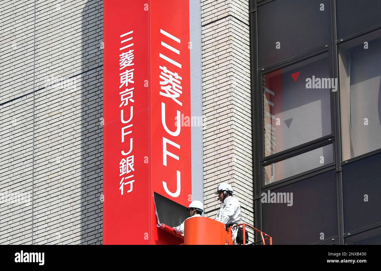 Workers unveil a signboard of MUFG Bank in Chiyoda, Tokyo. Mitsubishi Tokyo UFJ Bank changed its ...