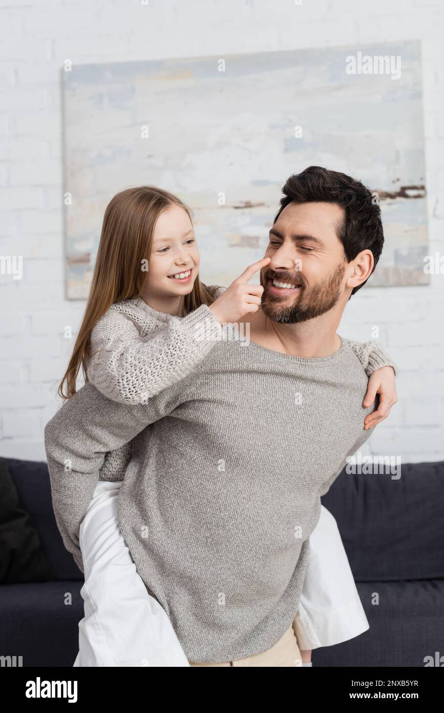 cheerful girl touching nose of bearded dad smiling with closed eyes ...