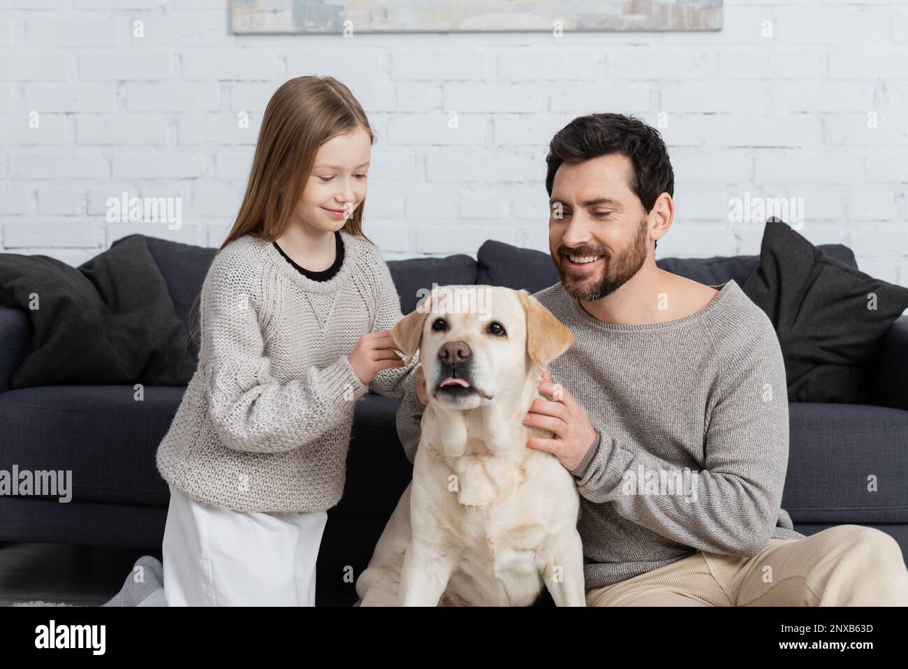 smiling father and daughter petting labrador dog sticking out tongue in ...