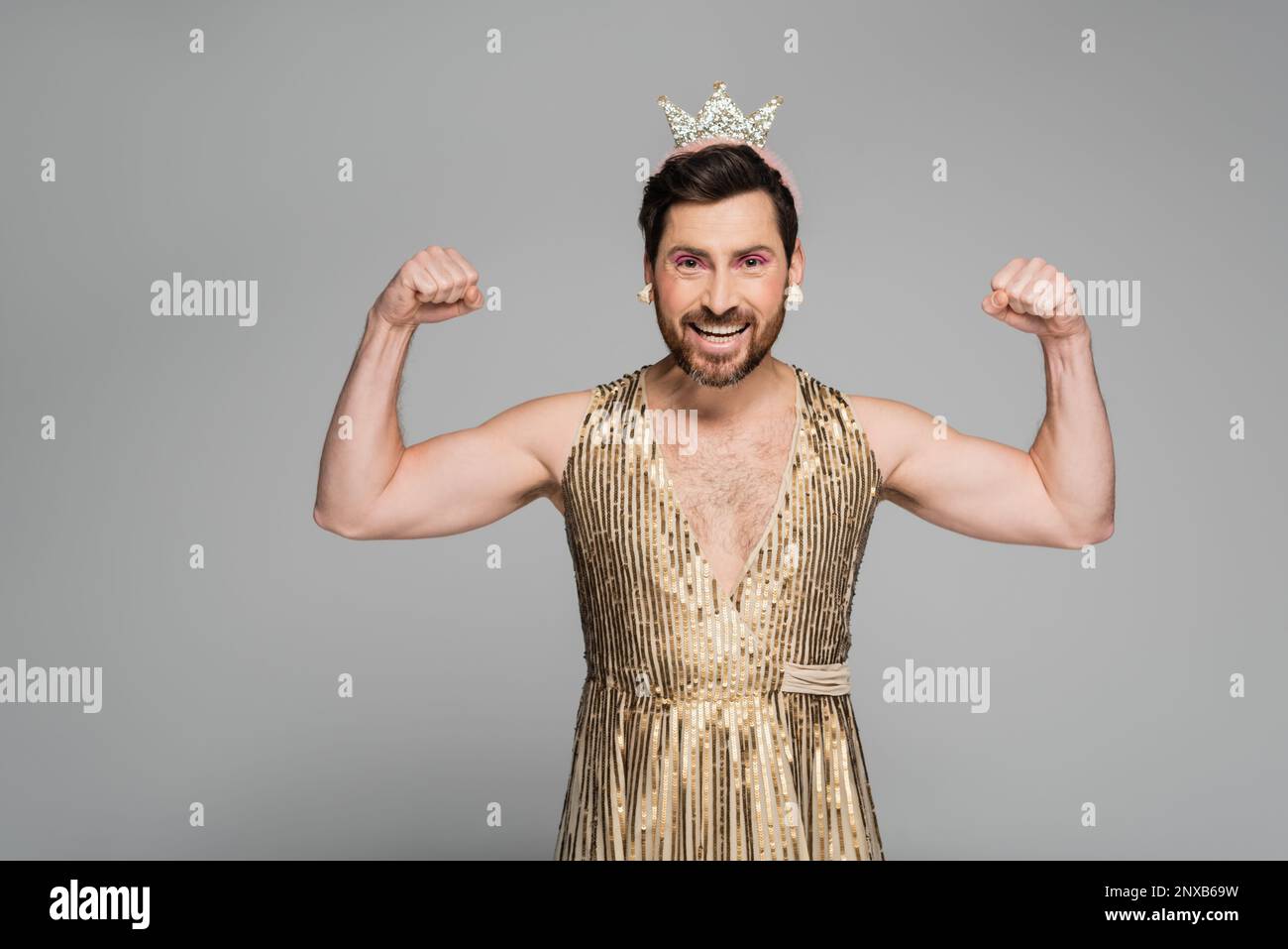 bearded man with toy crown on head and princess dress costume showing ...
