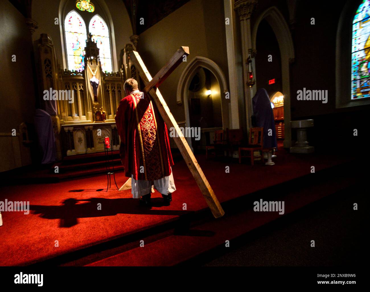 Father Justin Baker carries the cross to the mantel on Good Friday, on ...