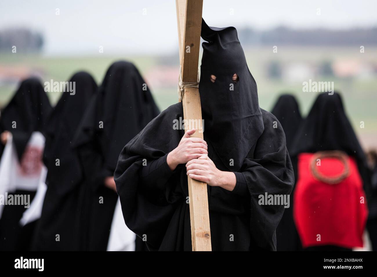 A cross bearer is followed by veiled women known as "les Pleureuses" or ...