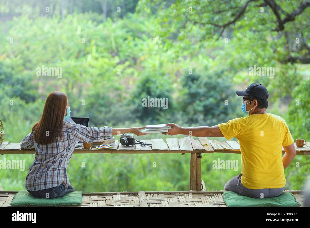 Rear view of two people passing books to each other, Bangkok, Thailand ...
