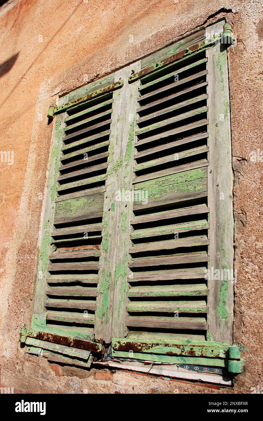Old light green wooden shutter in orang colored house facade Stock ...
