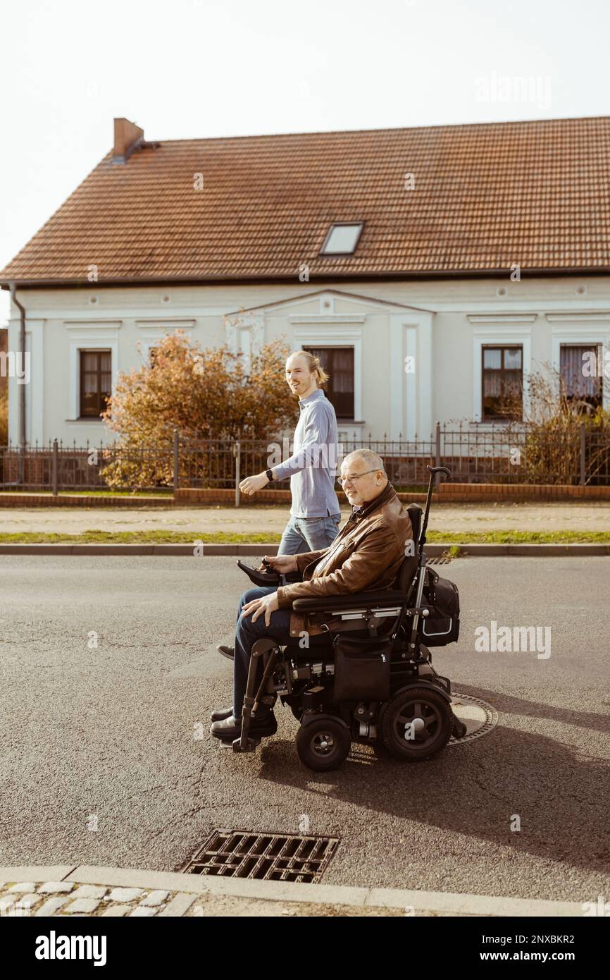 Side view of senior man with disability in motorized wheelchair by ...