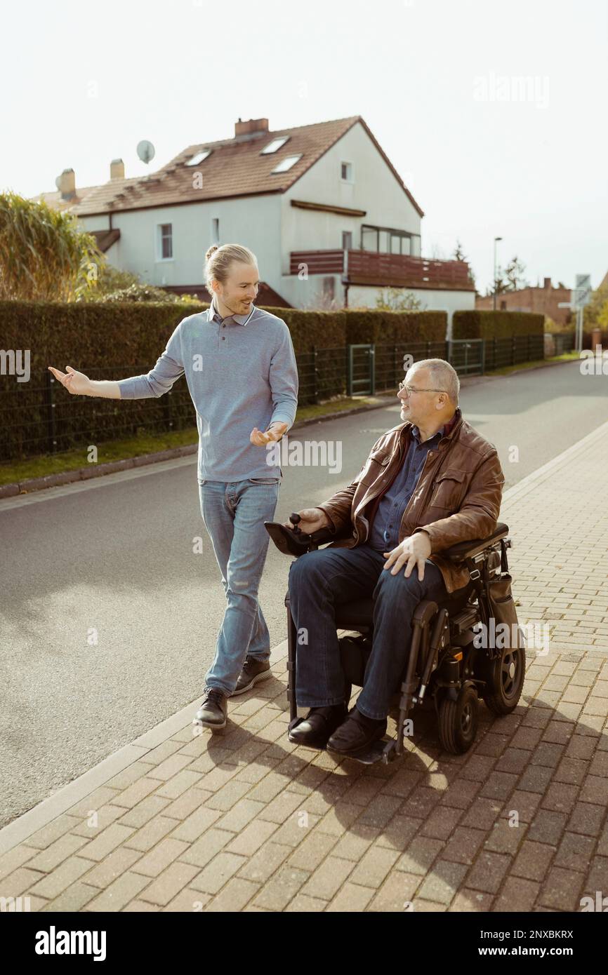 Full length of smiling senior man with disability in motorized ...