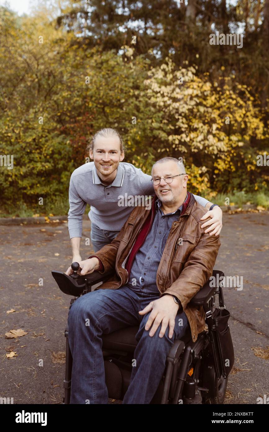Portrait of smiling young man with arm around father in motorized ...