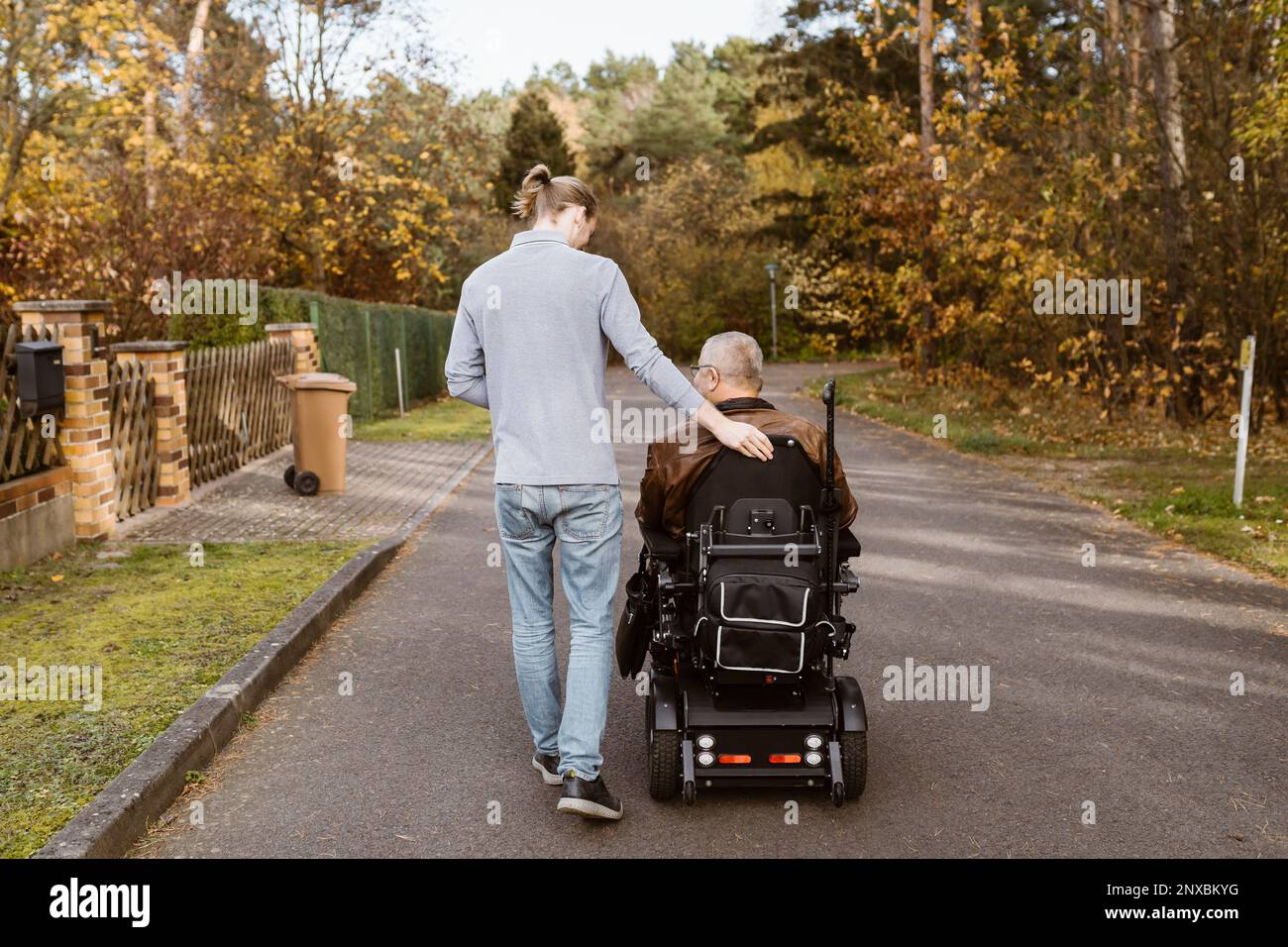 Full length of young male caregiver walking by senior man with ...