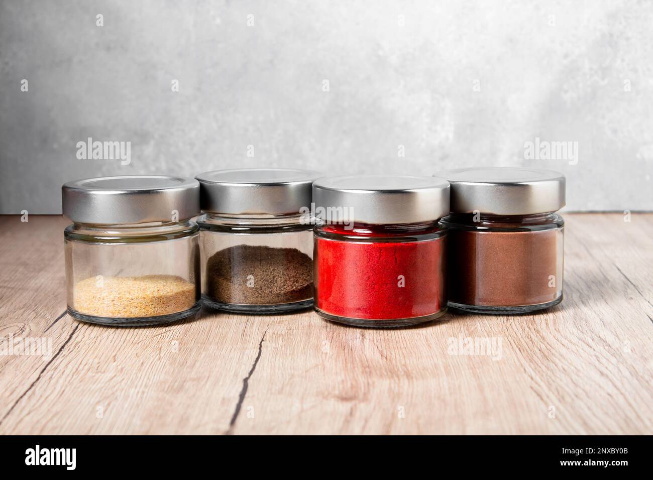 Bright fragrant spices in glass jars of different sizes on a wooden ...