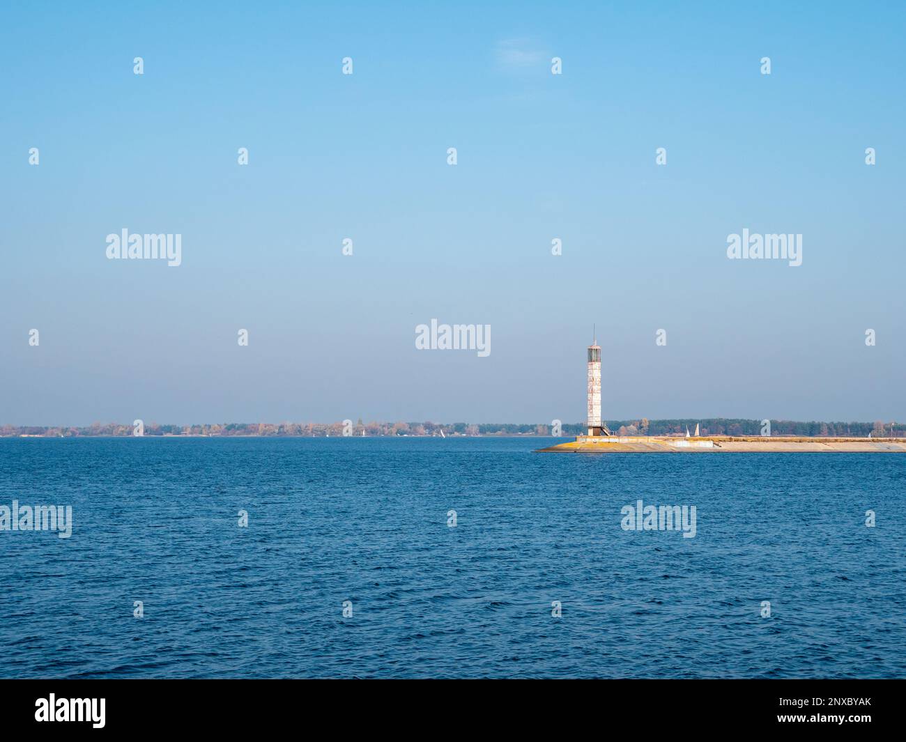 Old concrete lighthouse on the edge of the Kyiv sea spit, calm blue ...
