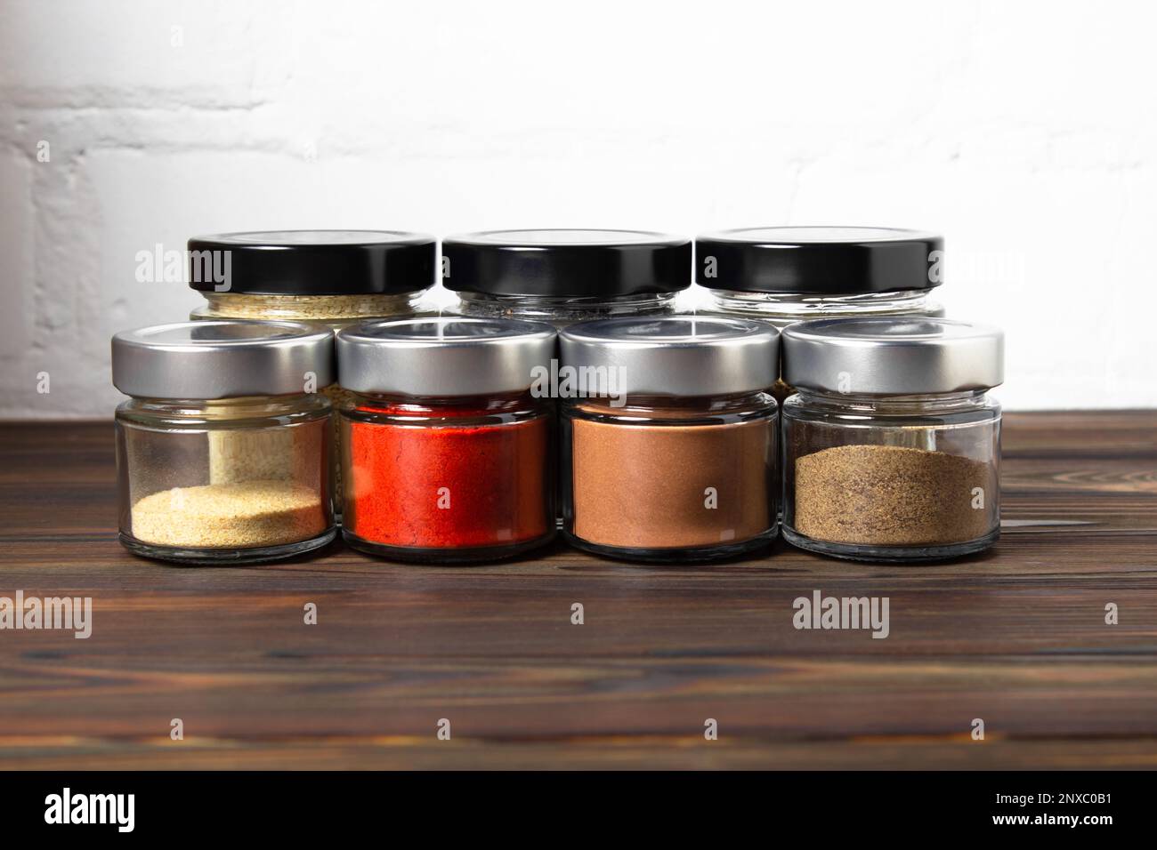 Bright fragrant spices in glass jars of different sizes on a wooden ...