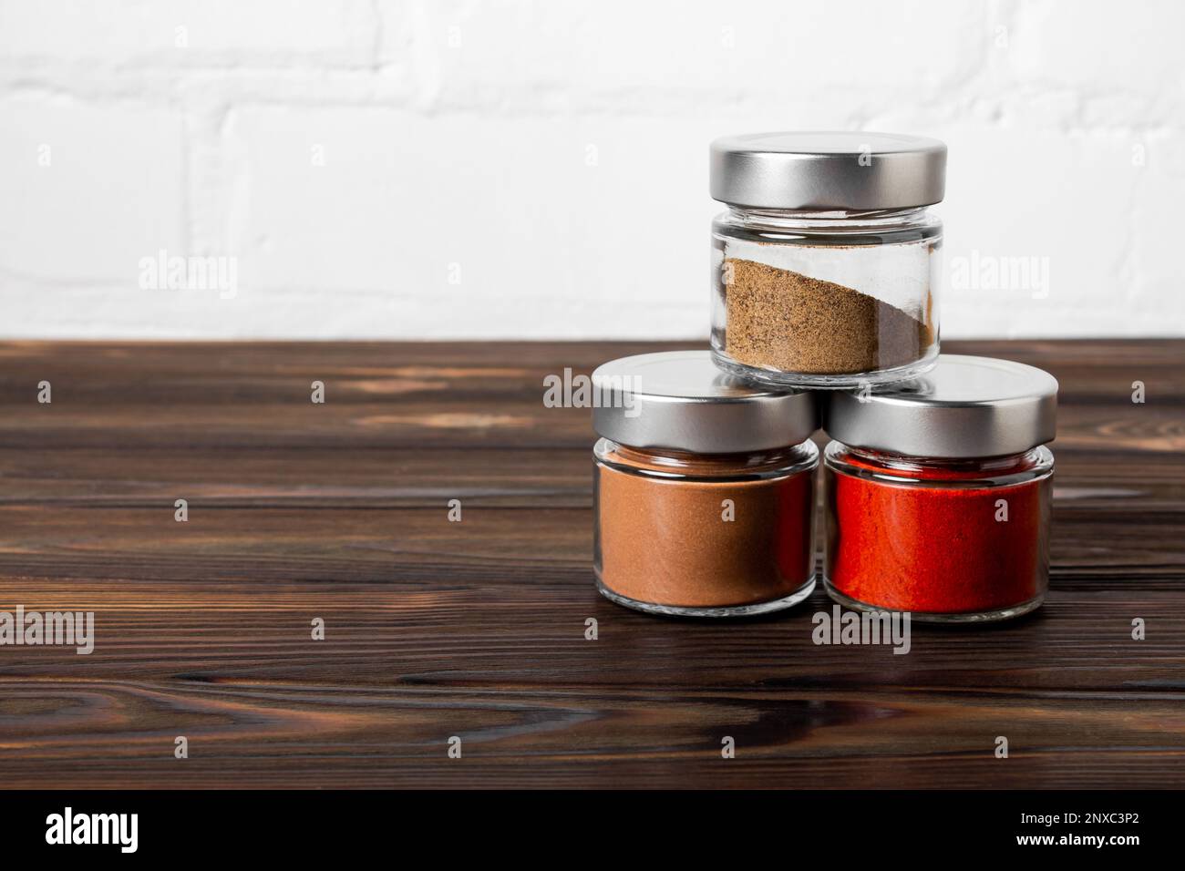 Bright fragrant spices in glass jars of different sizes on a wooden ...