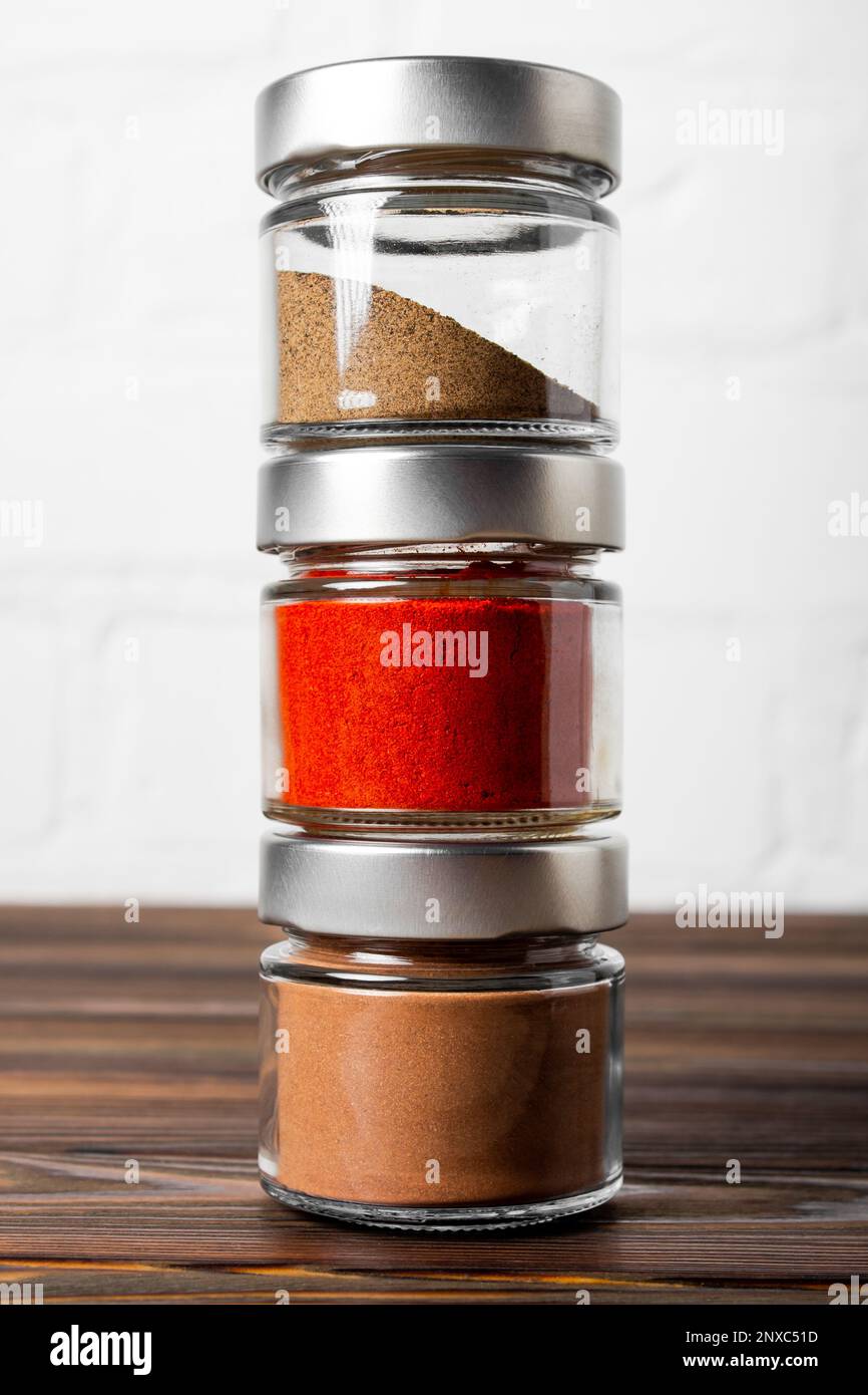 Bright fragrant spices in glass jars of different sizes on a wooden ...