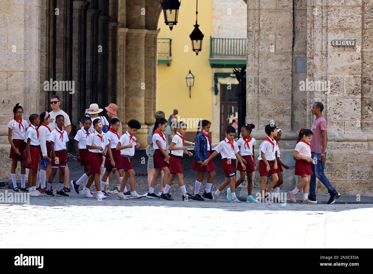 Cuban school children in pioneer ties walking on old city street during ...