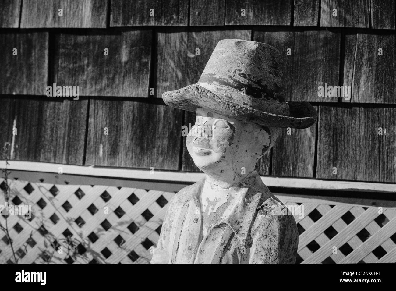 A vintage weathered statue of a boy sitting by the sea along the ...