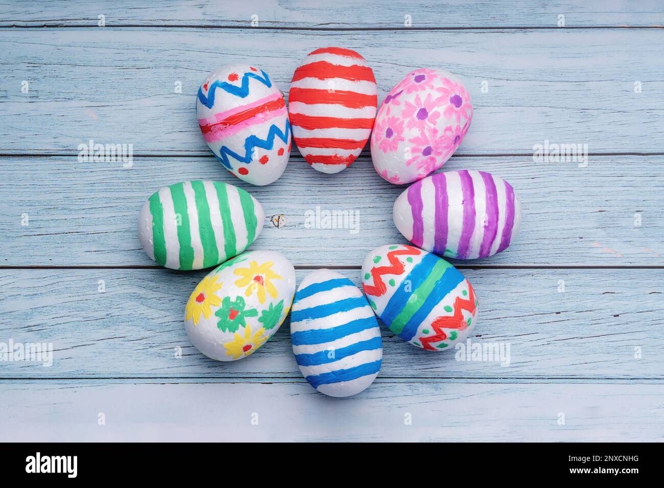 Colorful Easter eggs arranged in a circular pattern on a pastel blue ...