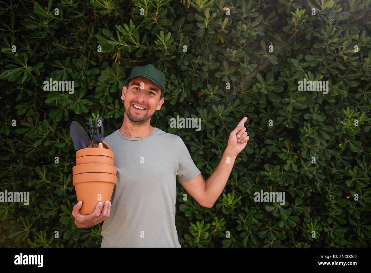 Man gardener in green cap holds terracotta clay pots with gardening ...