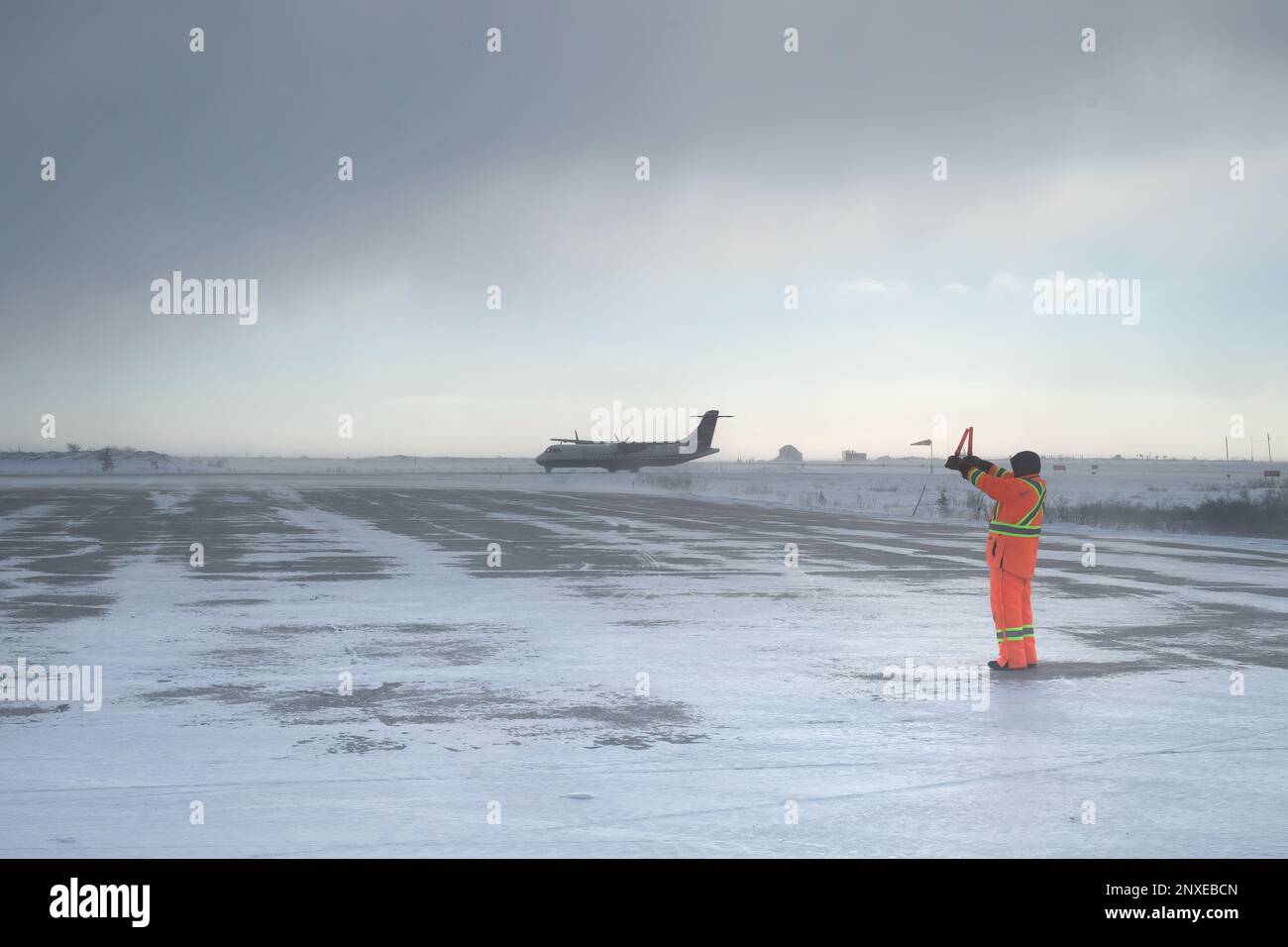 A worker guides a ATR 72 twin engine turboprop aircraft on the runway ...