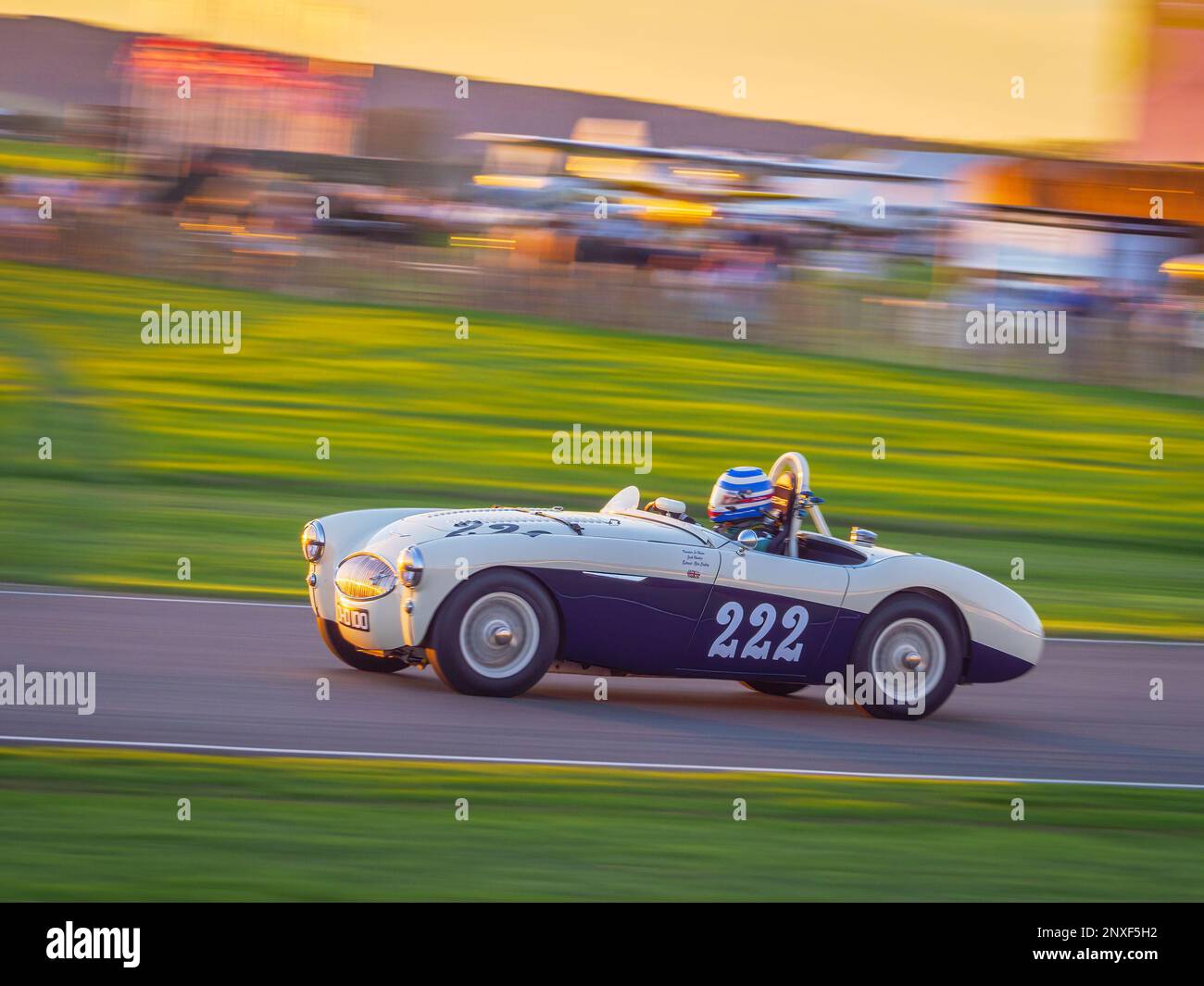 1955 Austin Healey 100S racing at sunset at the Goodwood Revival 2022 ...