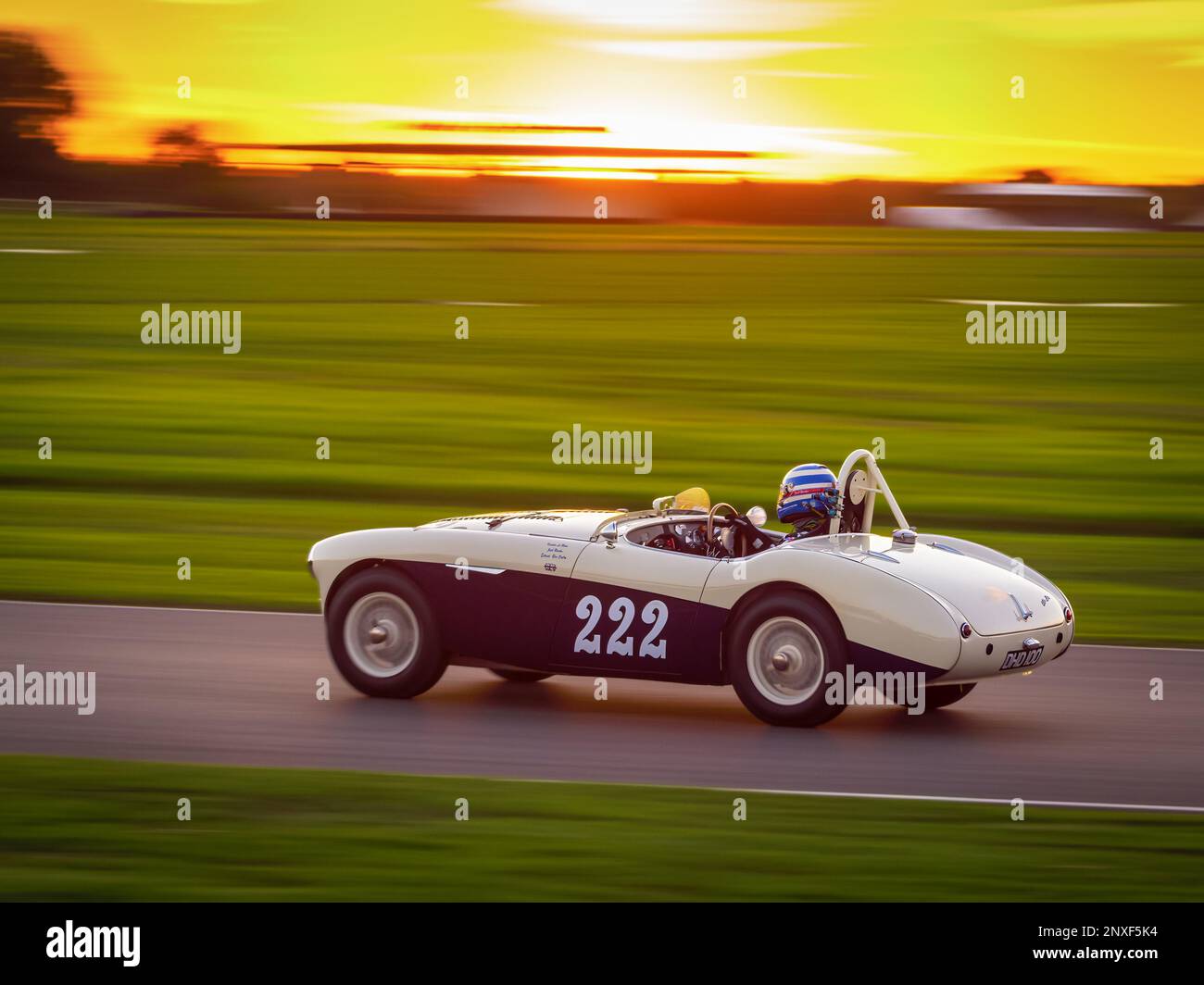1955 Austin Healey 100S racing at sunset at the Goodwood Revival 2022 ...