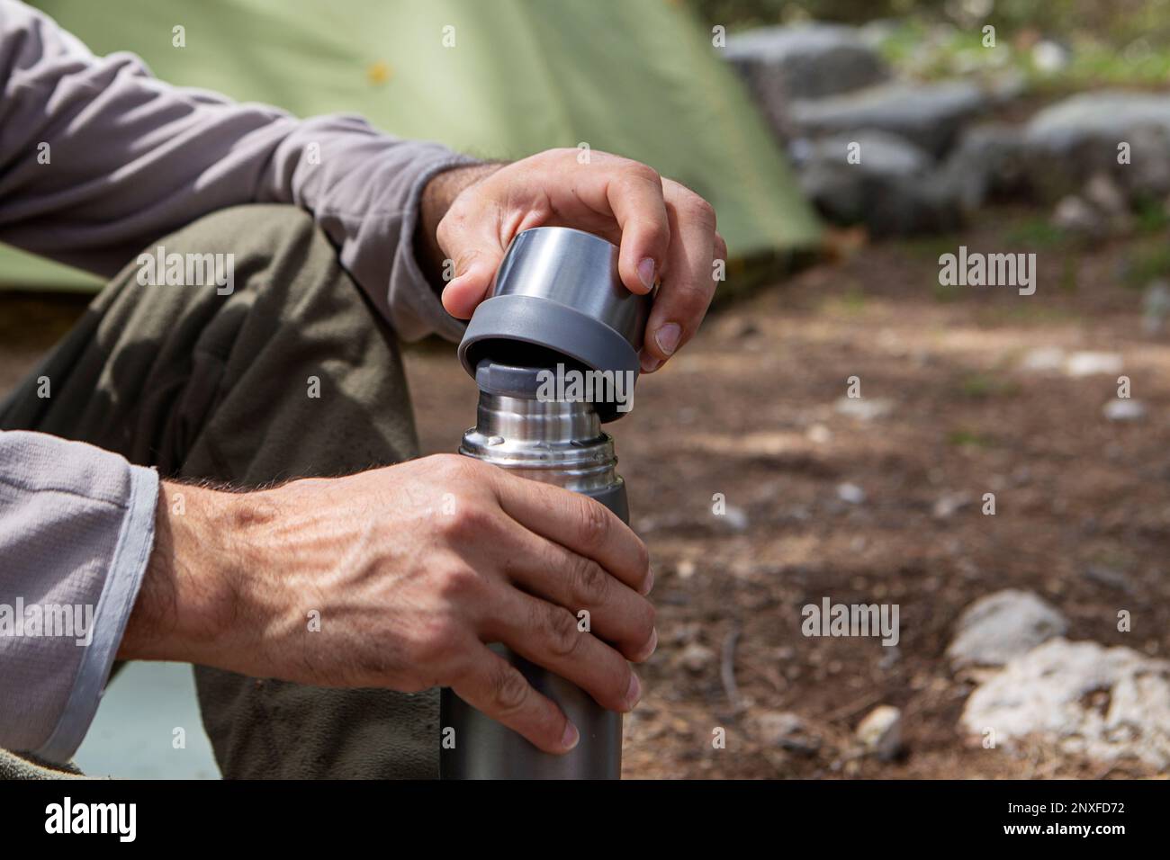 Man places thermos flask cups on a tree stump Stock Photo - Alamy