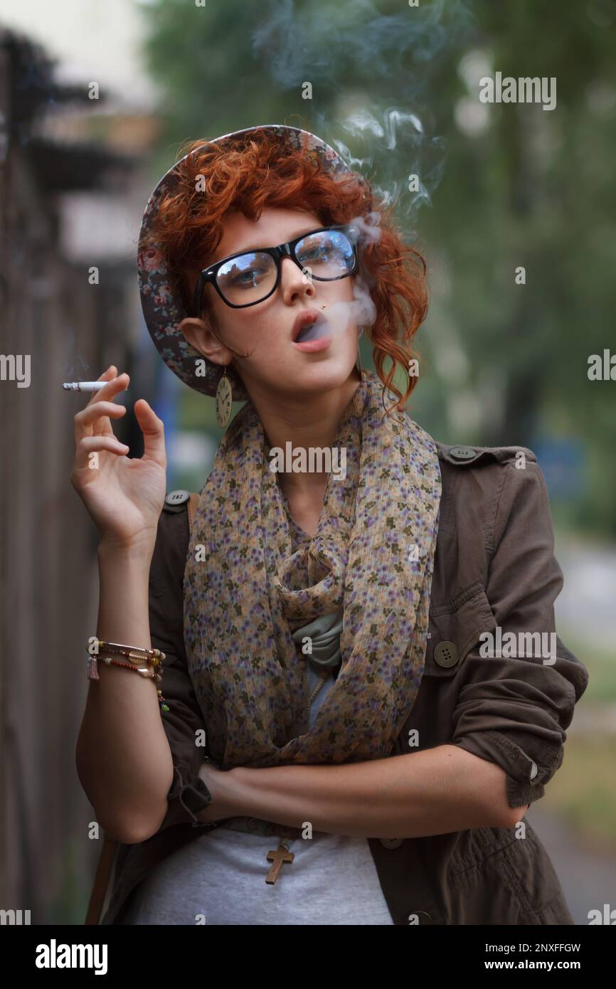 Teenager girl smoking a cigarette. Stylish young woman wearing ...